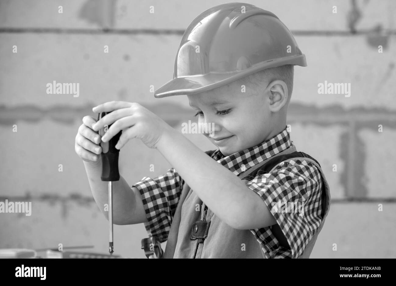 Child play with supplies, tools saw, hammer, screwdriver, helmet ...