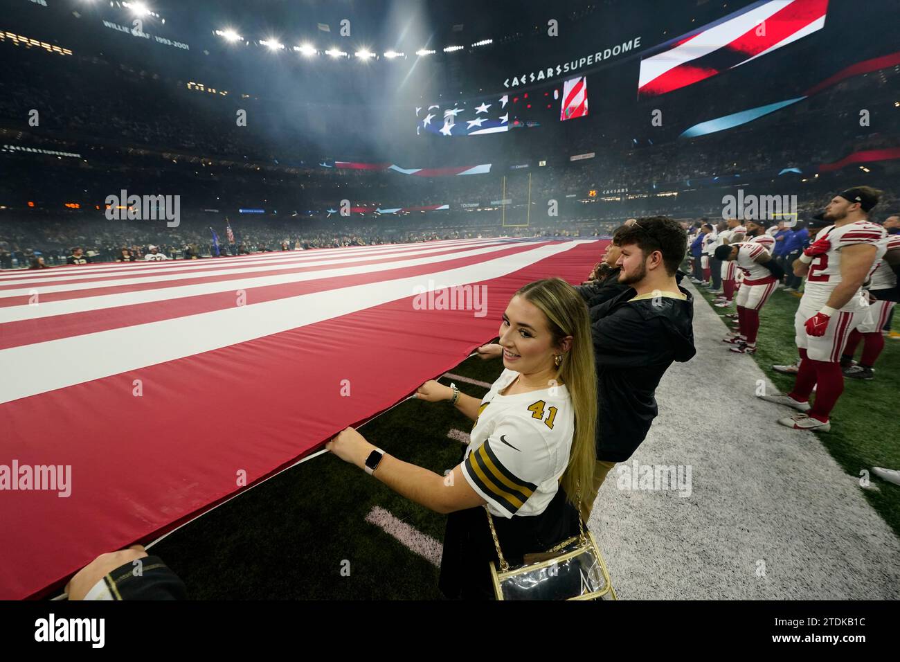 Volunteers unfurl a giant American flag during the playing of the ...