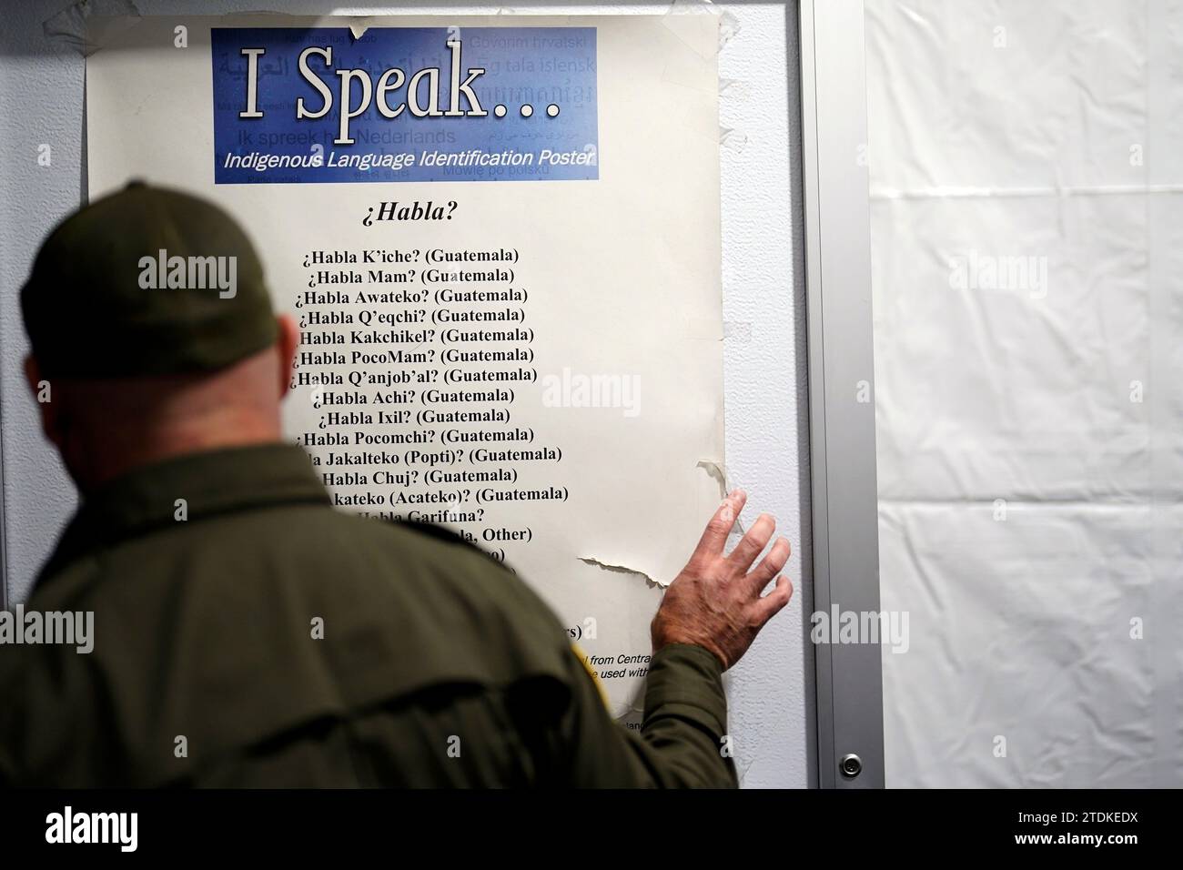 A Border Patrol agent passes a poster designed to help communicate with ...