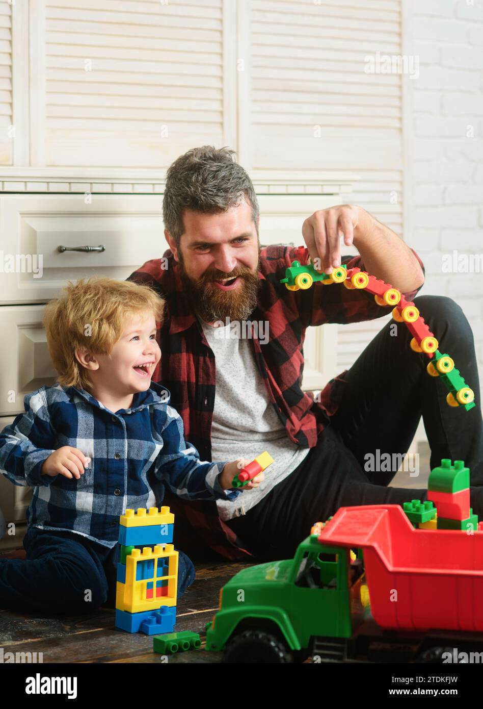 Father and son create toys from bricks. Dad and kid build of plastic ...
