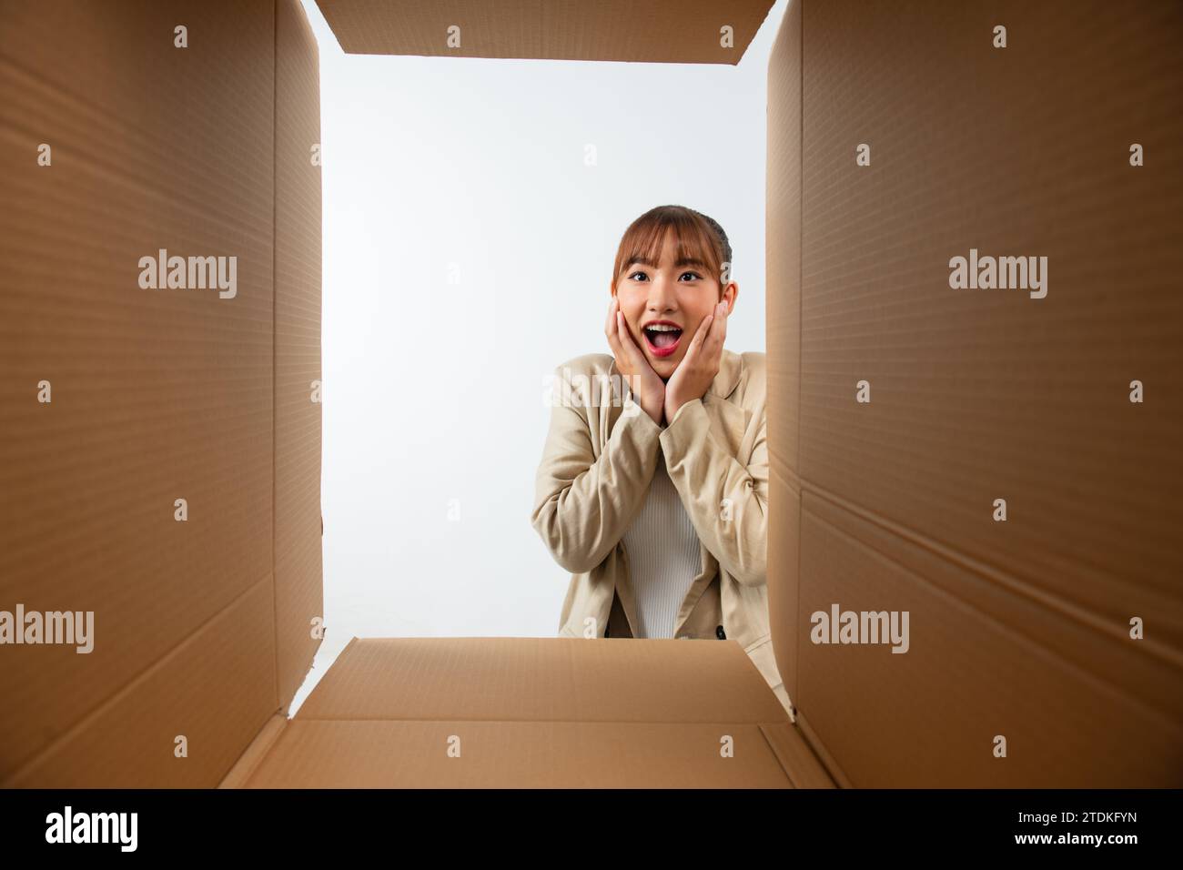 Happy laughing young woman putting arms into box, feeling excited ...