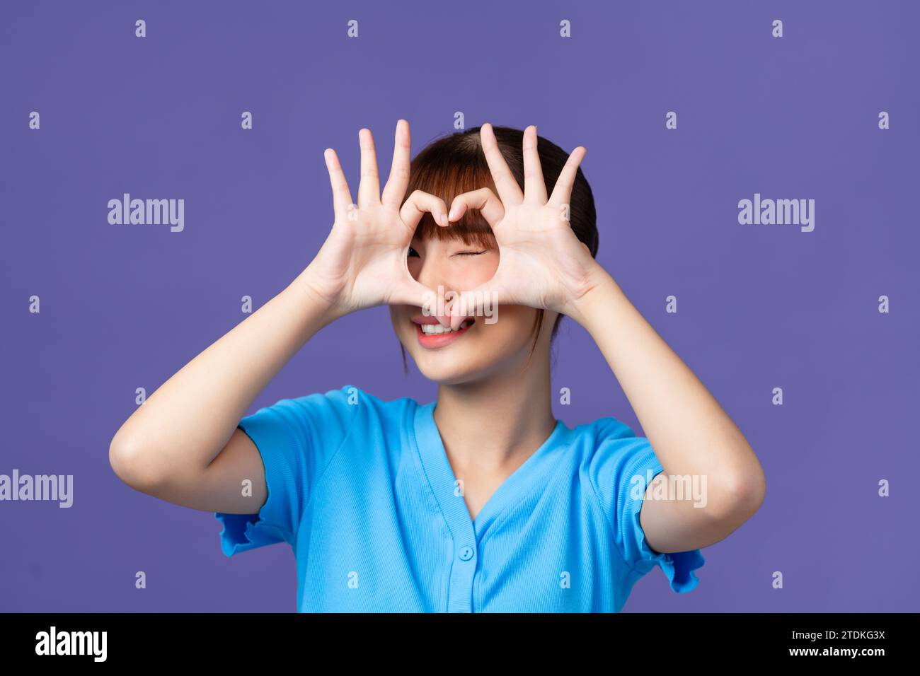 Young beautiful asian woman doing heart shape with hand and fingers ...