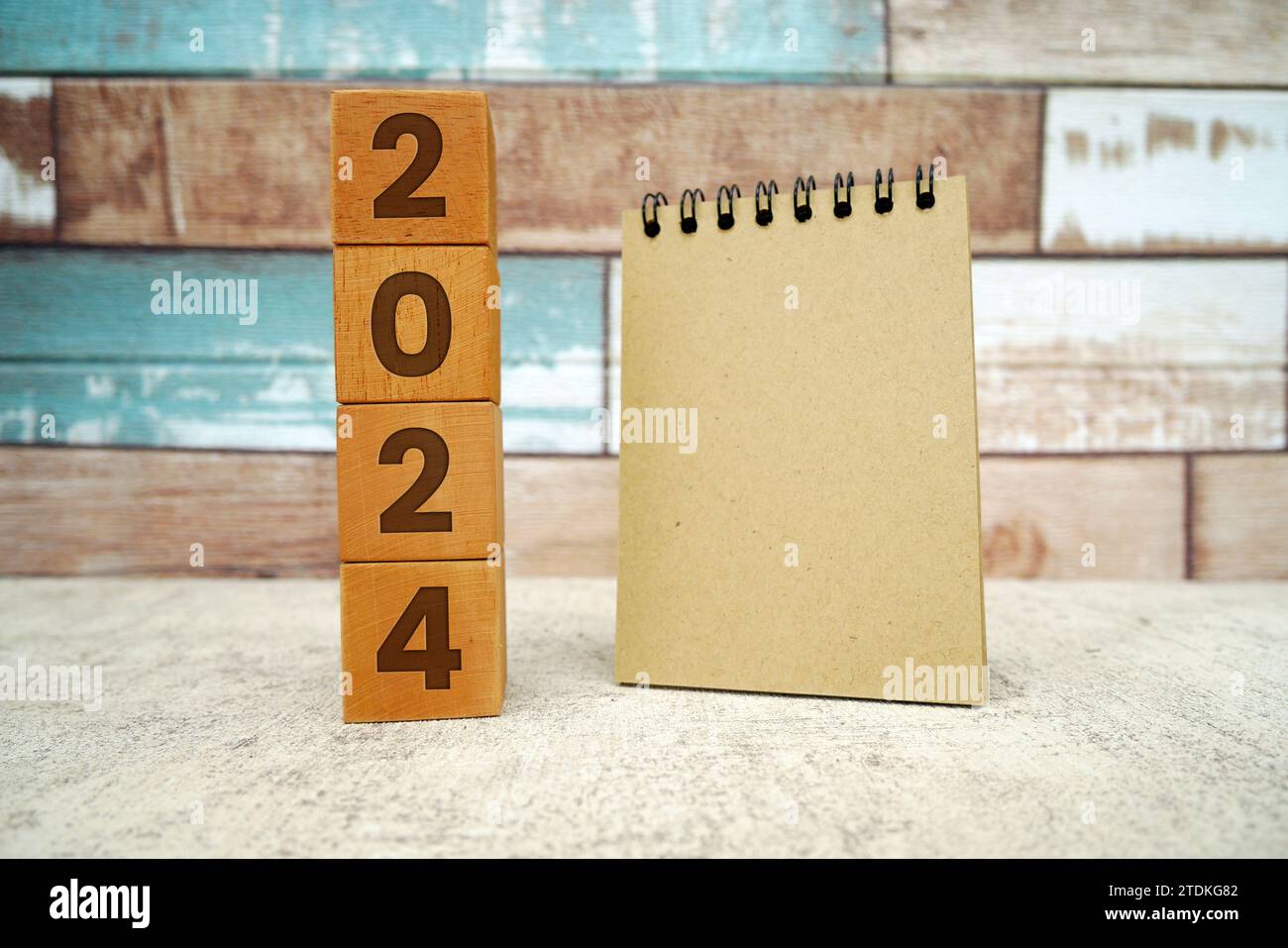 Wooden cubes with 2024 text and blank notebook paper on a brick wall ...