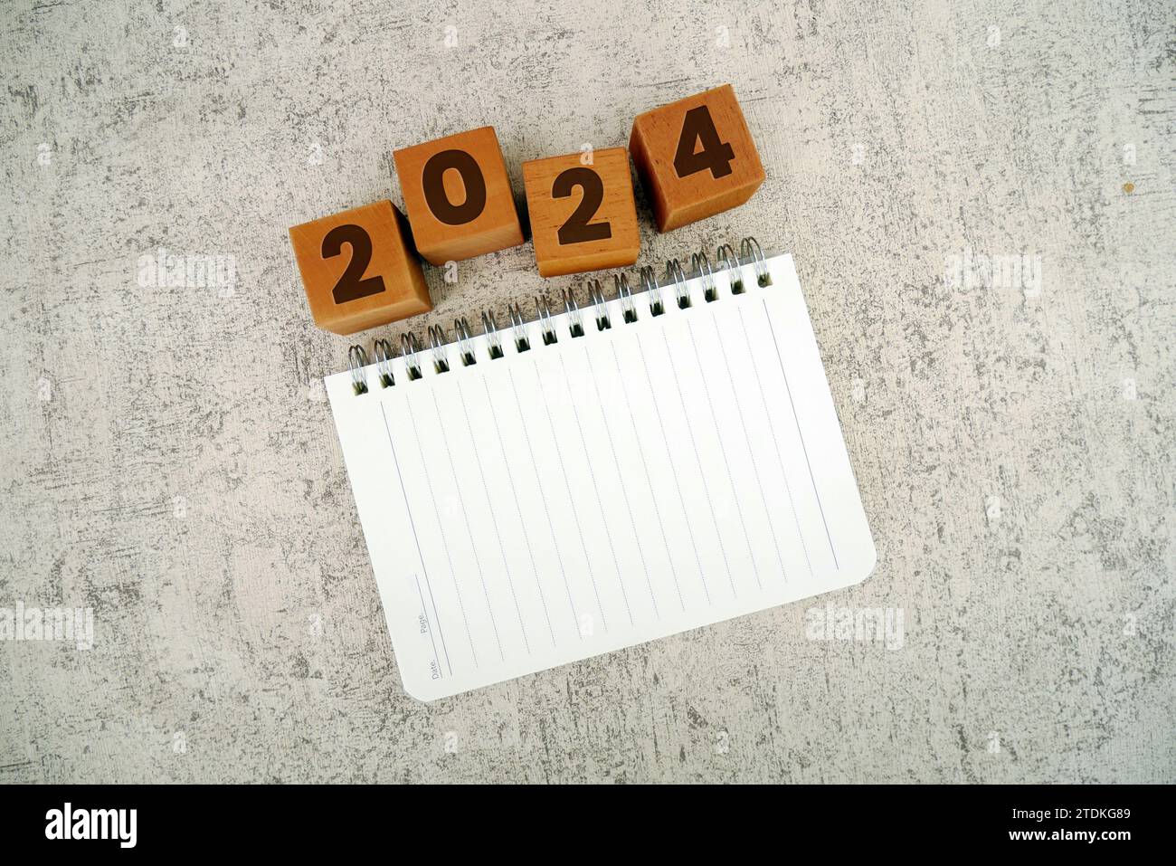 Wooden cubes with 2024 text and blank notebook paper on a brick wall ...