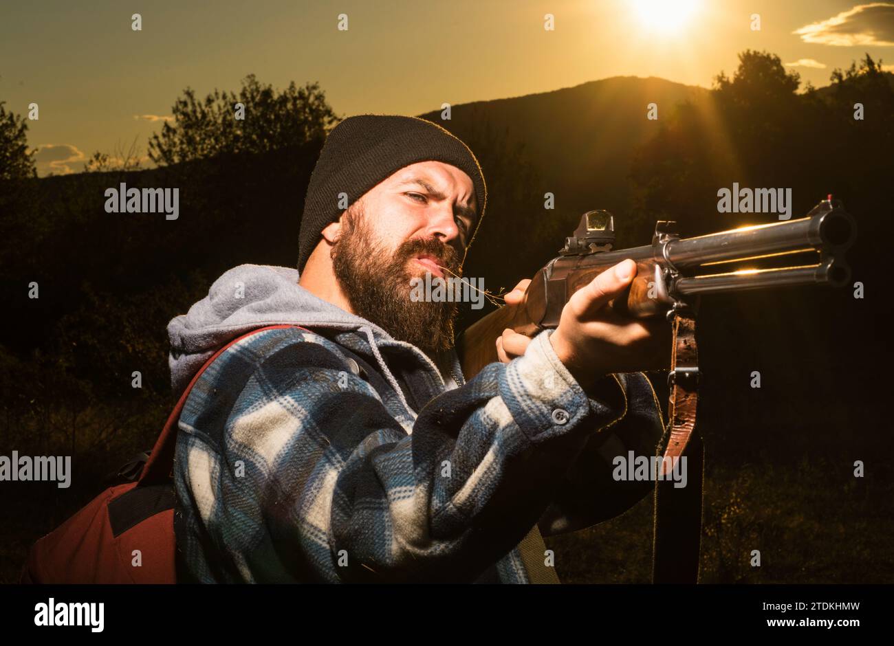 Bearded hunter man holding gun and walking in forest. Rifle Hunter ...