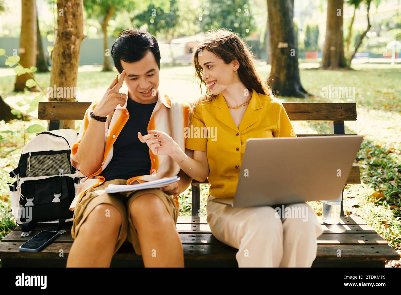 Smiling girl helping friend with solving math equation when they are ...