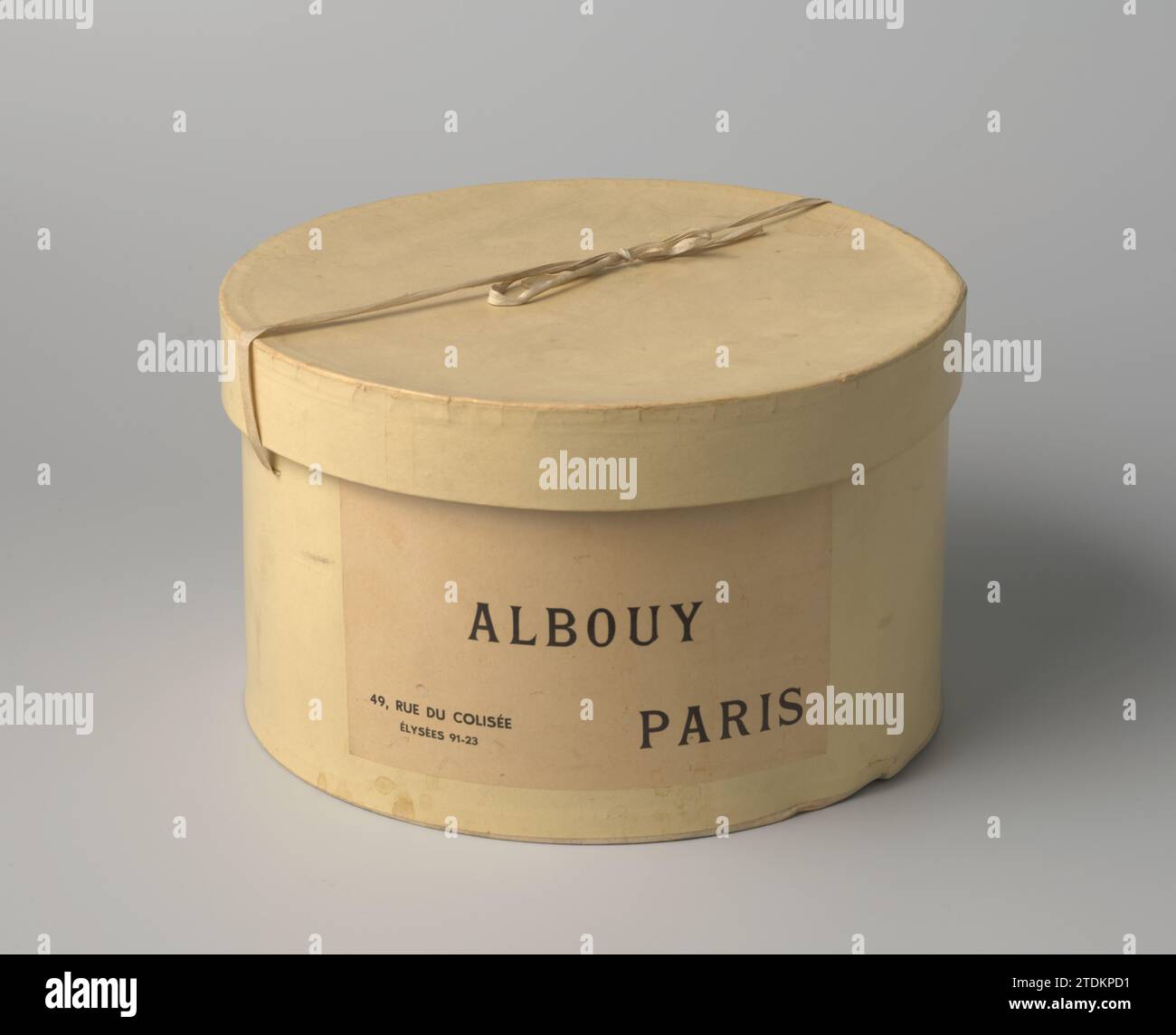 Round cardboard hat box with loose lid, covered with beige paper ...