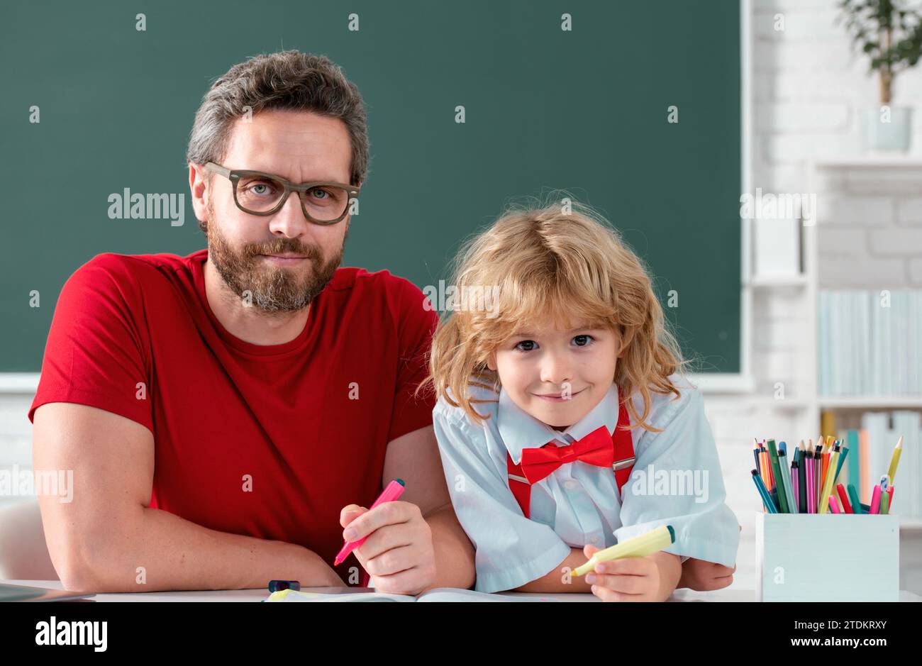 Tutor and child learning at school classroom. Teacher and little ...