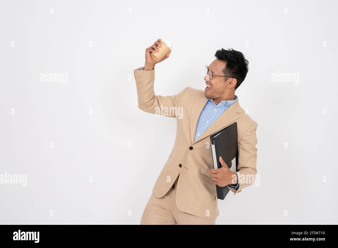 A cheerful and excited Asian businessman with a coffee cup and document ...