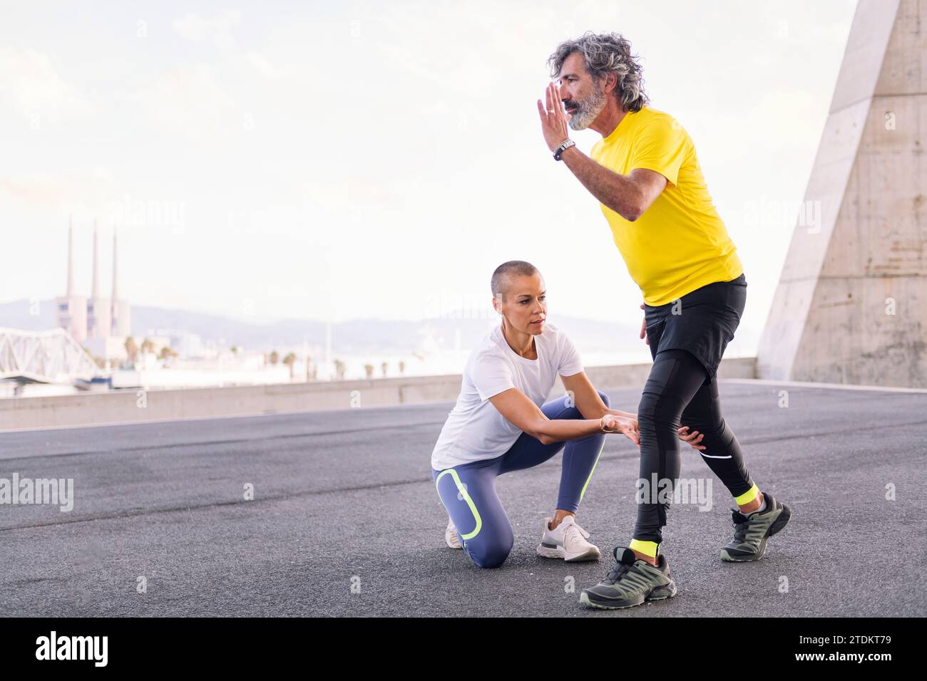 trainer correcting leg position of a sports man Stock Photo - Alamy