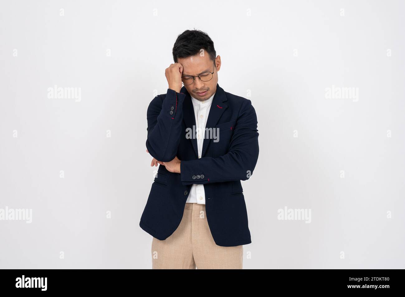 A stressed, failure Asian businessman stands on an isolated studio ...