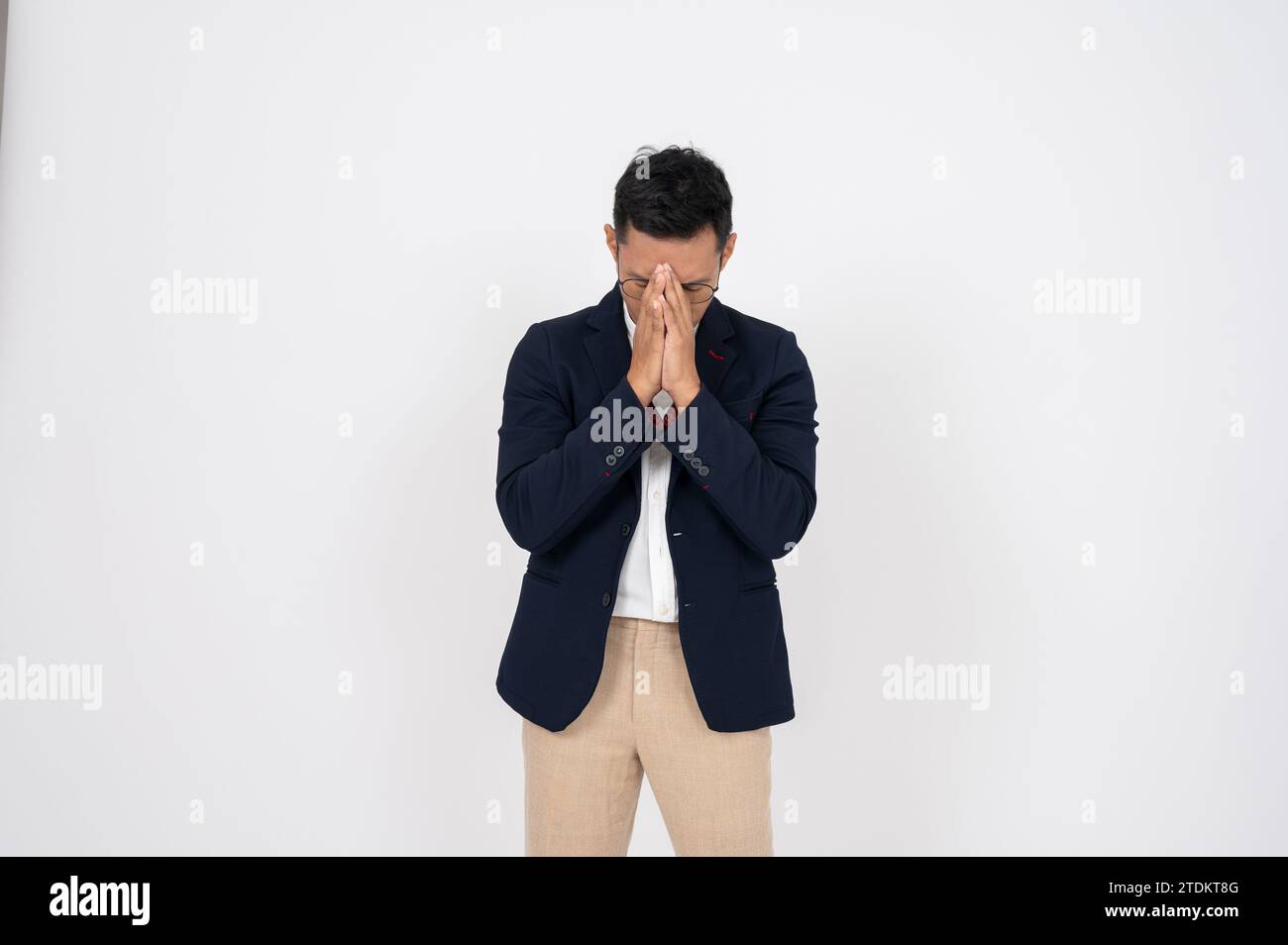 A stressed, failure Asian businessman stands on an isolated studio ...