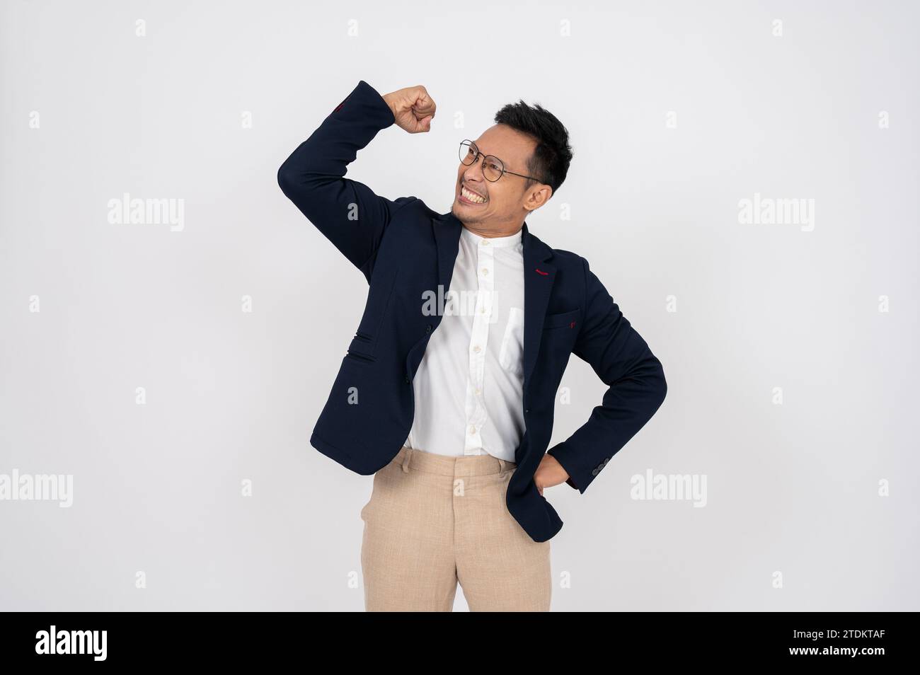 A positive, cheerful Asian businessman is showing his strong arm muscle ...