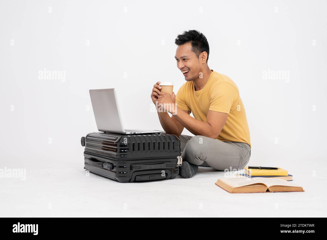 A happy Asian man is sitting on an isolated white studio background ...