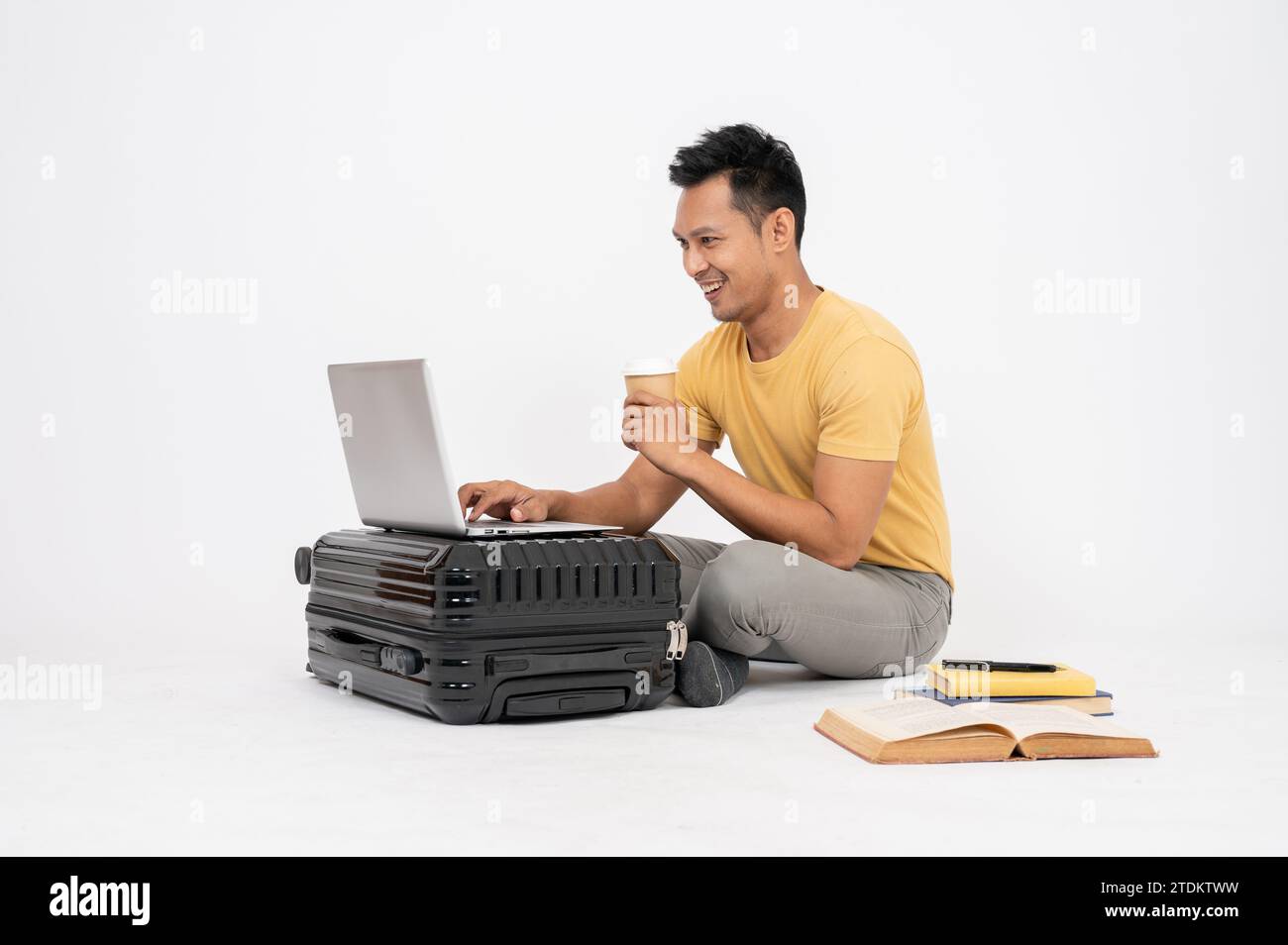 A happy Asian man is sitting on an isolated white studio background ...