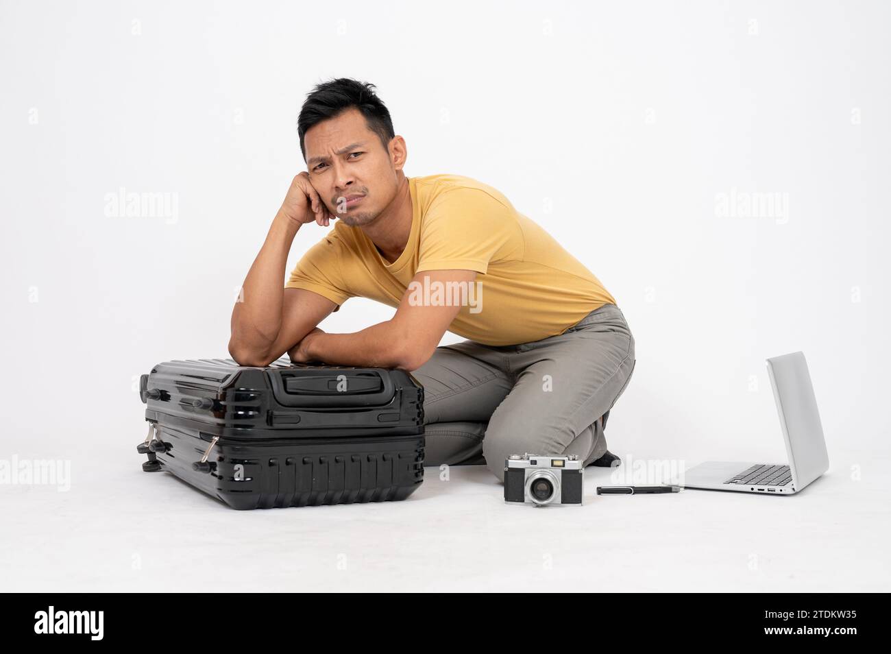 A sad and bored Asian man is sitting on an isolated white studio ...