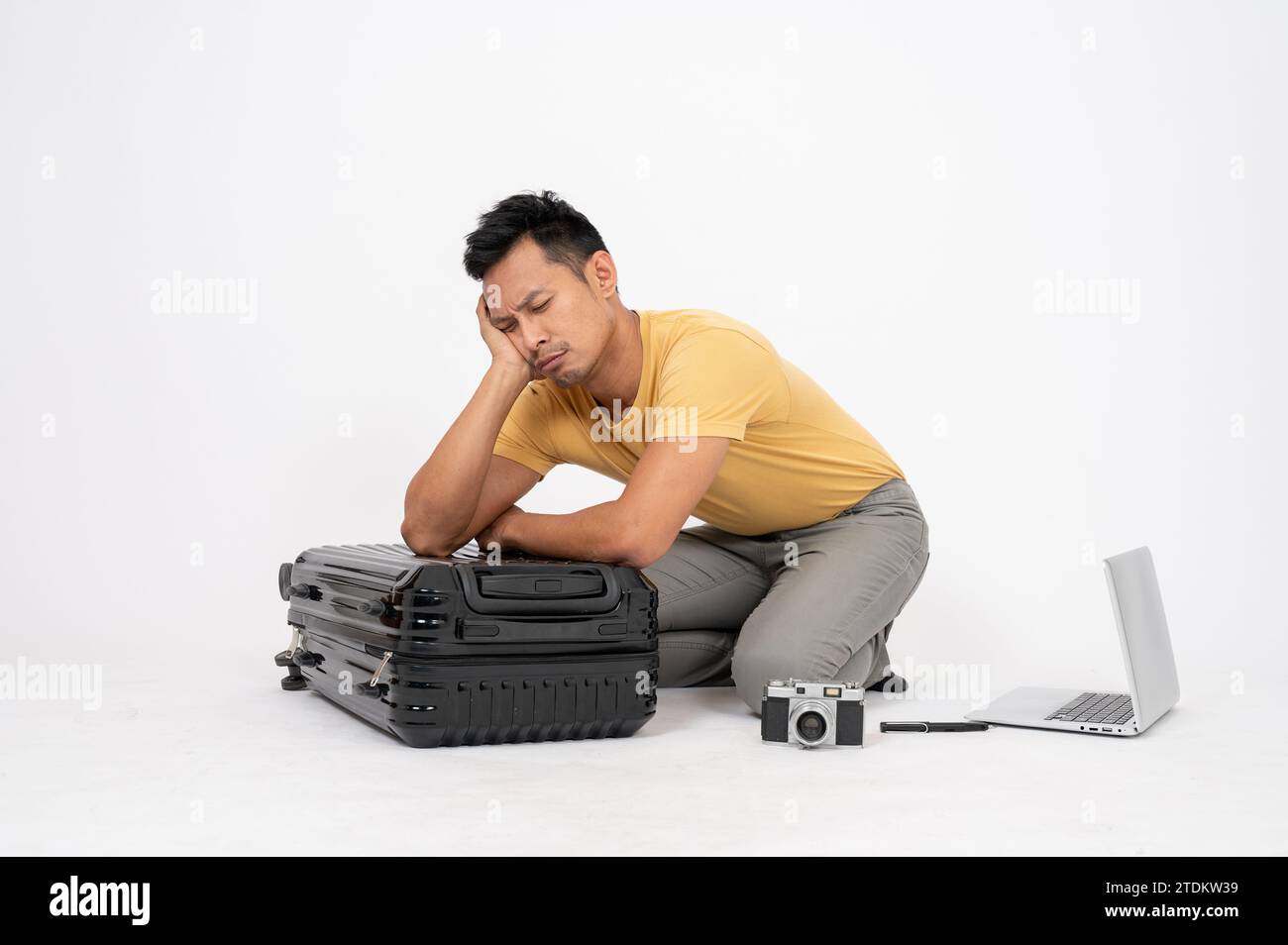 A sad and bored Asian man is sitting on an isolated white studio ...