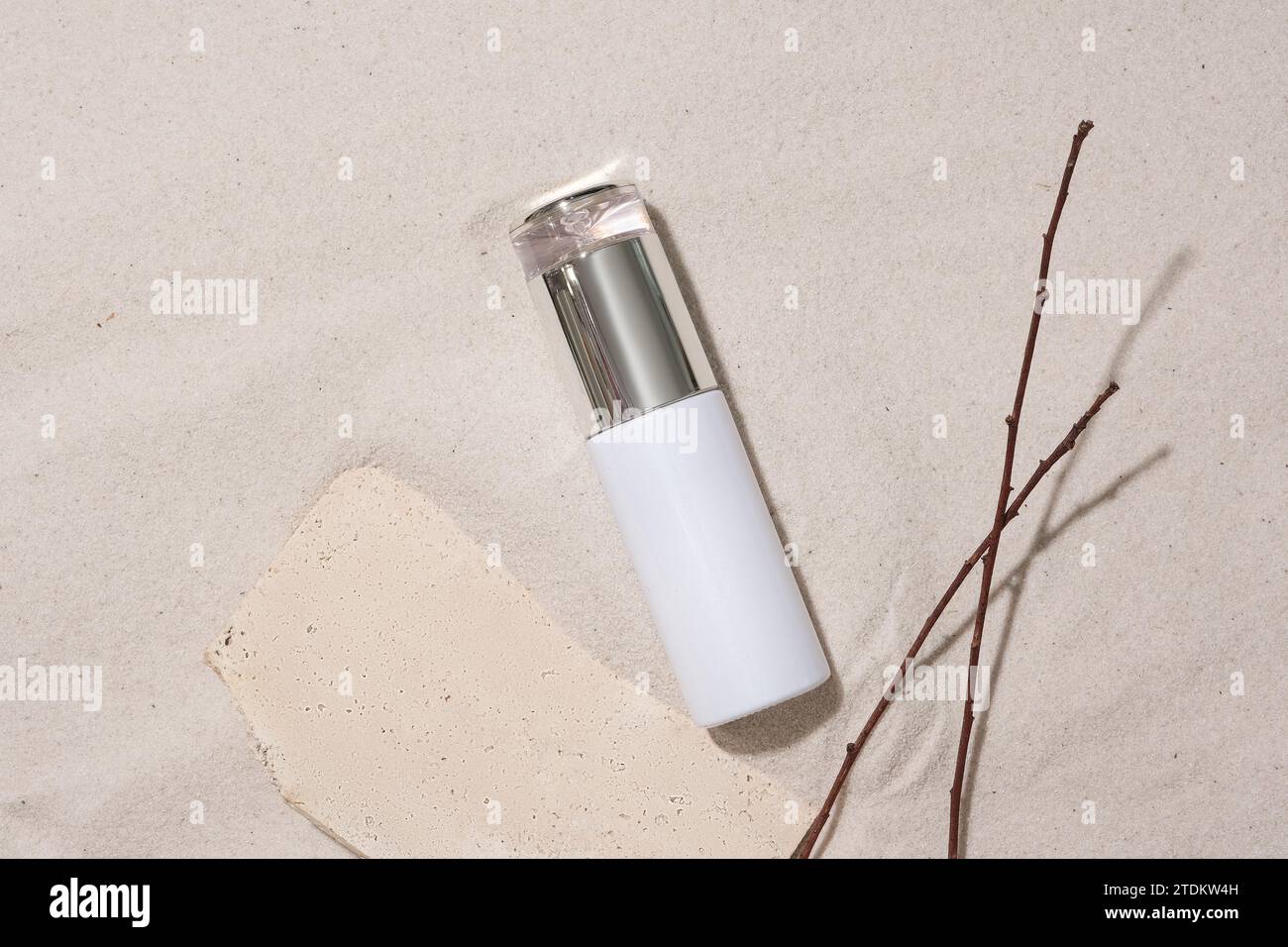 An unbranded luxury cosmetics bottle, a stone platform and dry branches ...