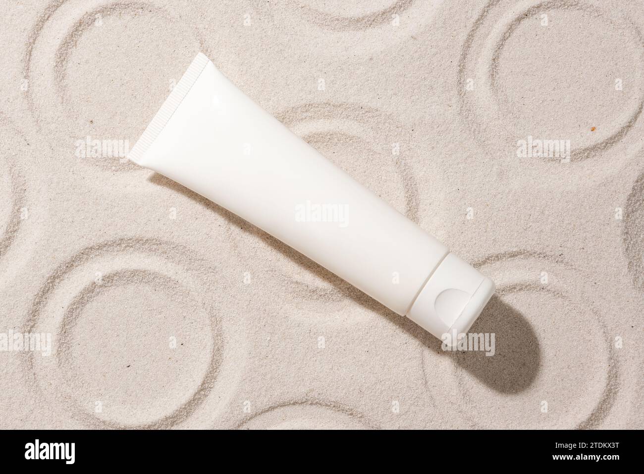 Flat lay of a tube of sunscreen displayed on a sandy background with ...