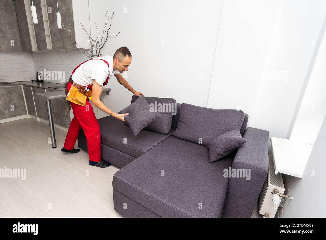 Loader moves sofa, couch. worker in overalls lifts up sofa, white ...