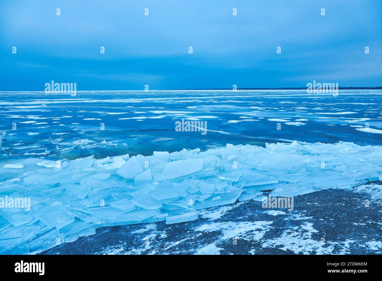 A striking winter view with a crystal-clear blue ice sheet gently ...