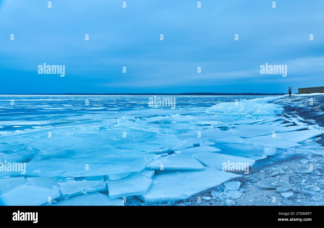 A striking winter view with a crystal-clear blue ice sheet gently ...
