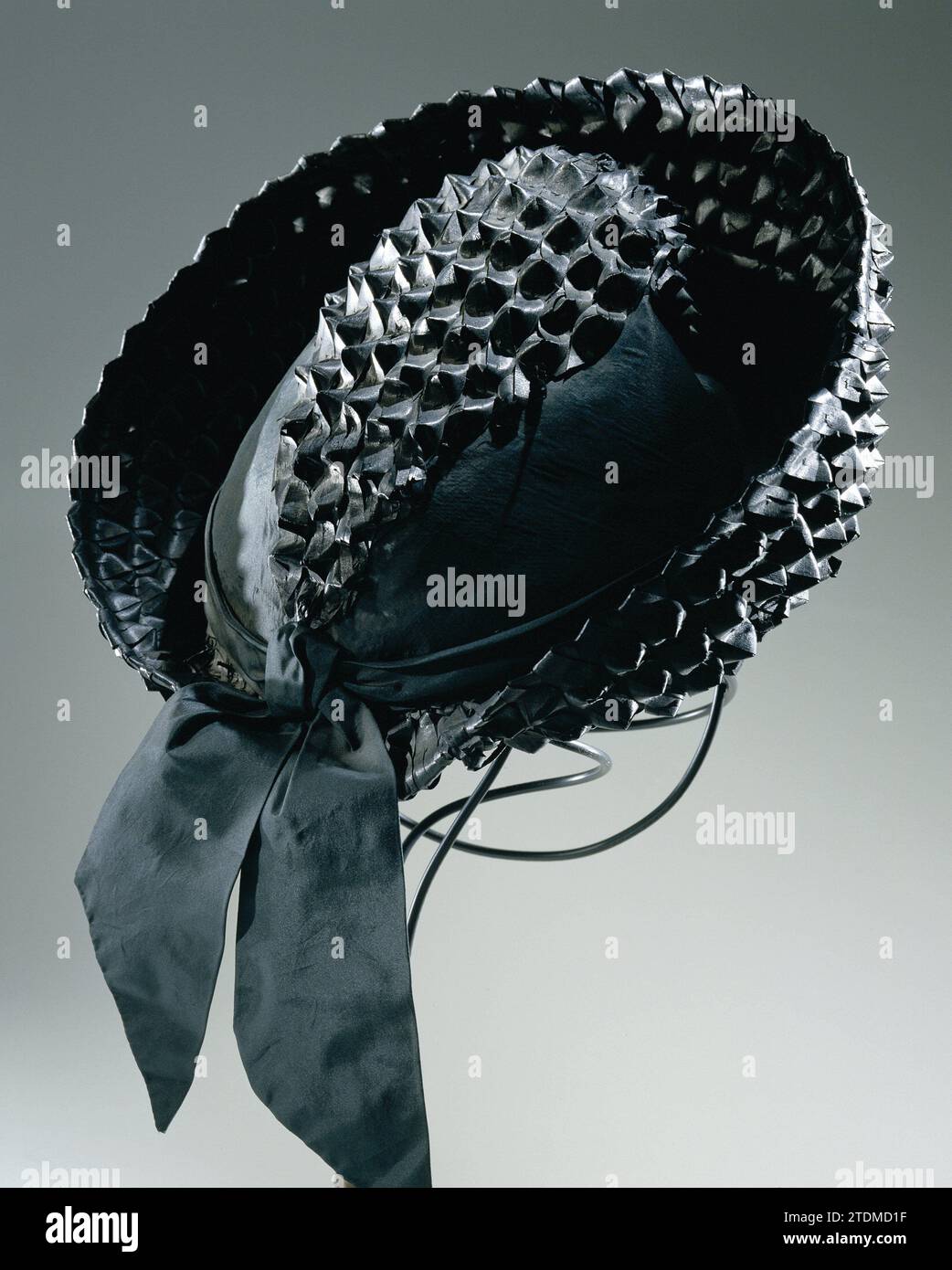 Hat of braided black raffia with a flat sphere and the front of the rim ...