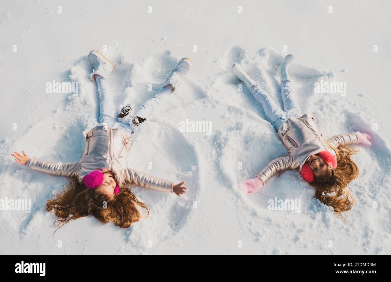 Two Girls on a snow angel shows. Smiling children lying on snow with ...