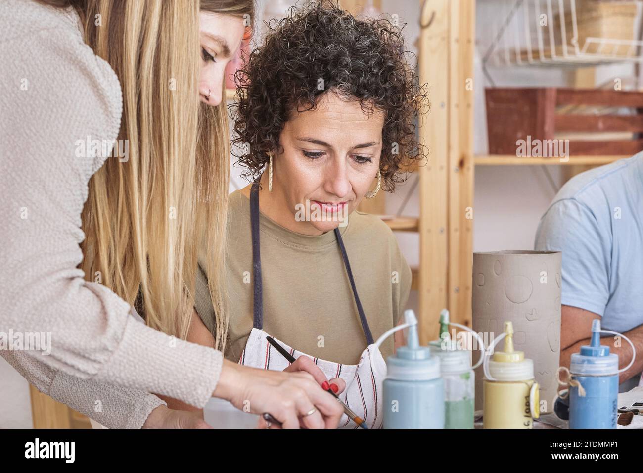 Two female potters concentrating on applying glaze to a ceramic piece ...
