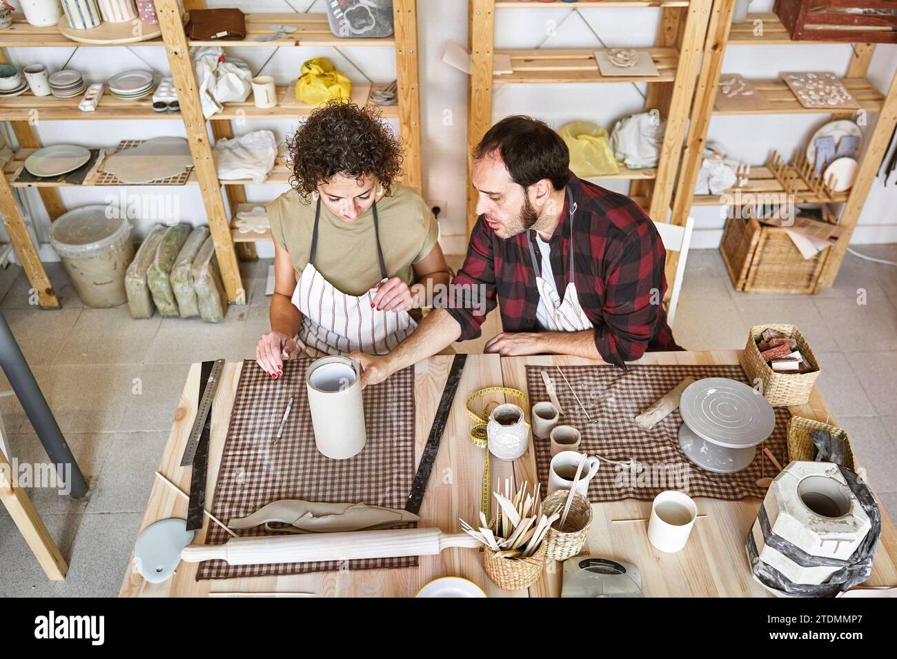 An experienced artisan guides an apprentice in ceramic techniques ...