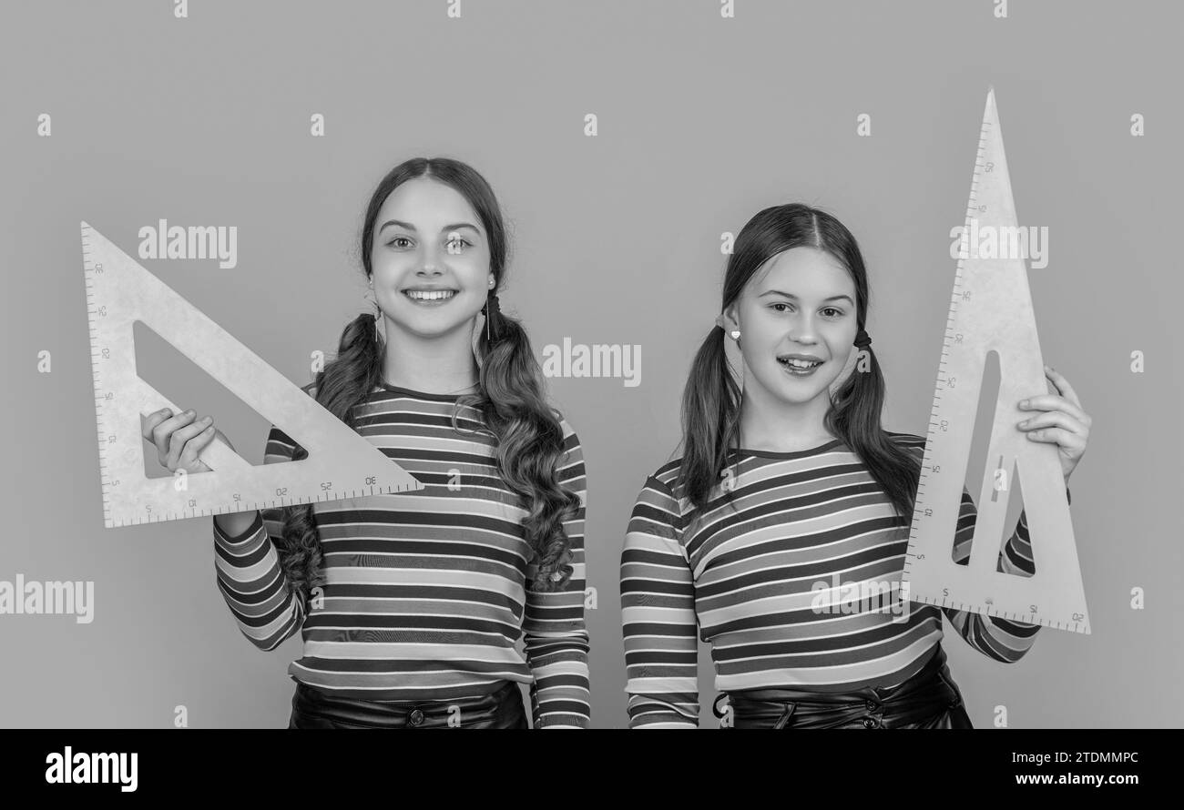 cheerful school children hold math tool of triangle Stock Photo - Alamy