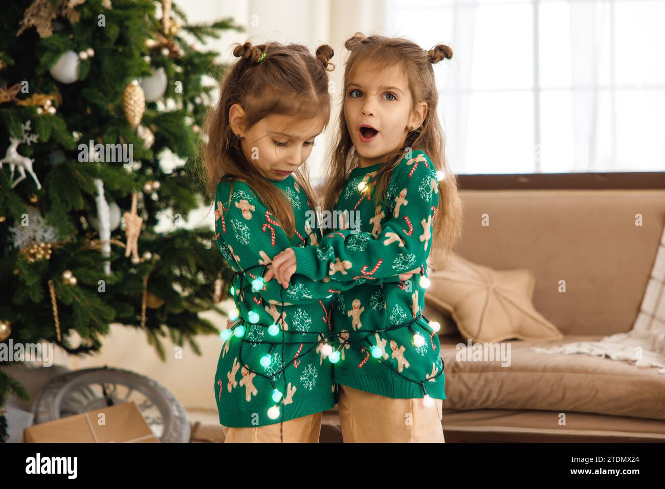 Two cute twin girls playing together on a christmas eve Stock Photo - Alamy