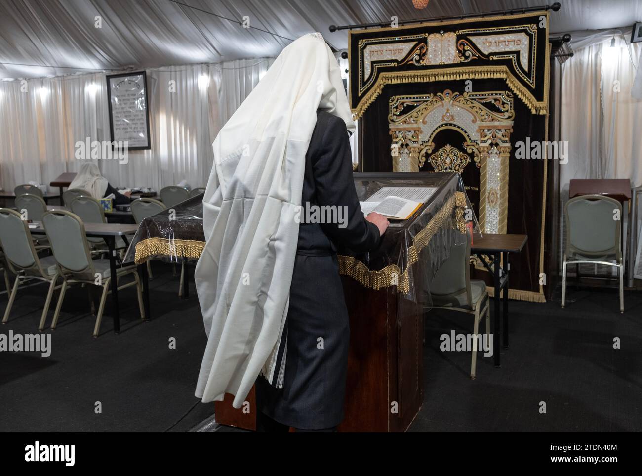 An anonymous orthodox Jewish man wearing a tallis prays alone at the ...