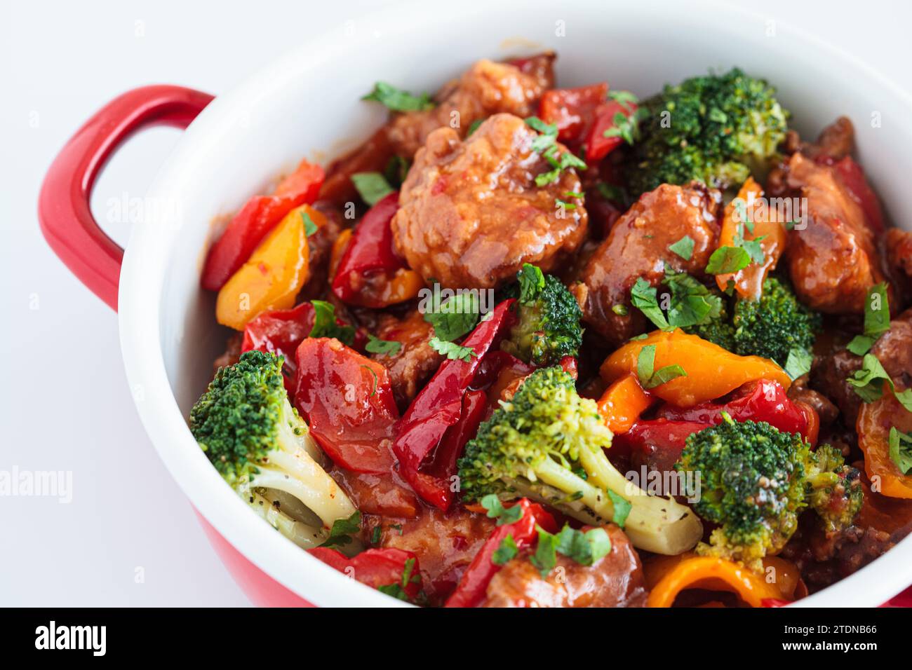 Stewed chicken fillet with vegetables in a pan, white background, close ...