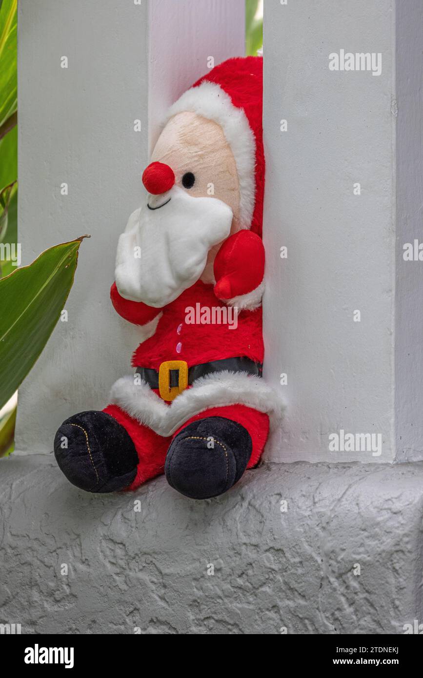 Santa toy dressed up, wedged between two columns at the porch of a ...