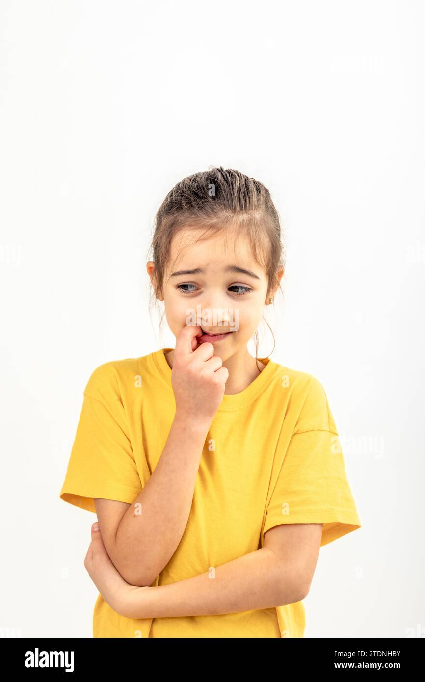 Scared and anxious girl, biting her fingernails on a white background ...