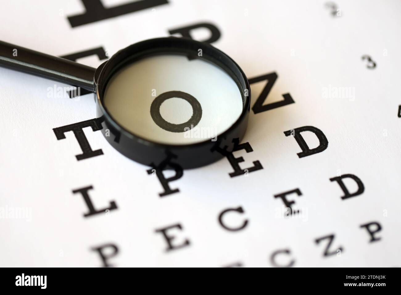Magnifier glass focuses eye chart letters clearly and lies on eye test ...