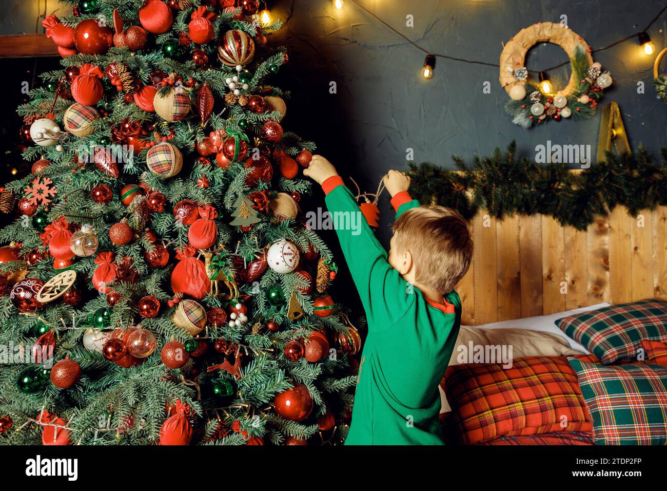 Child hanging a Christmas boot decoration illuminated on a Christmas ...