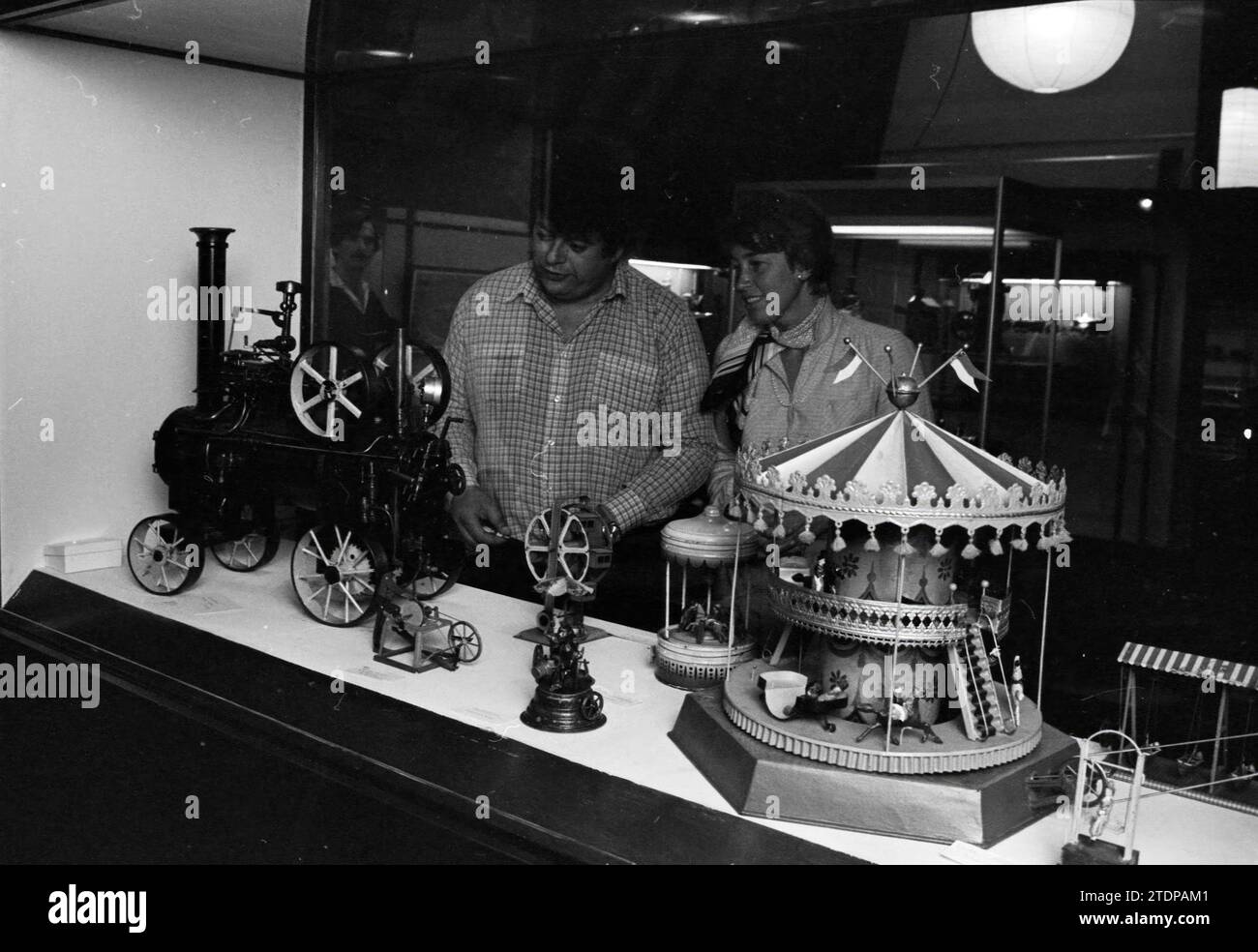 Man and woman at a display case with a miniature steam locomotive and ...