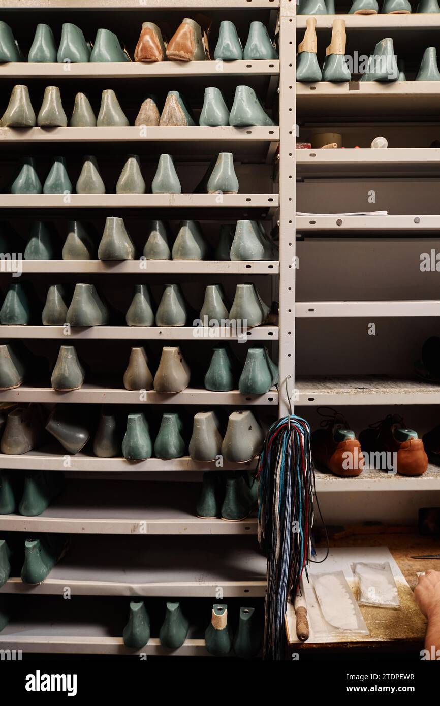 Part of wide and tall stand with many shelves with shoe workpieces ...