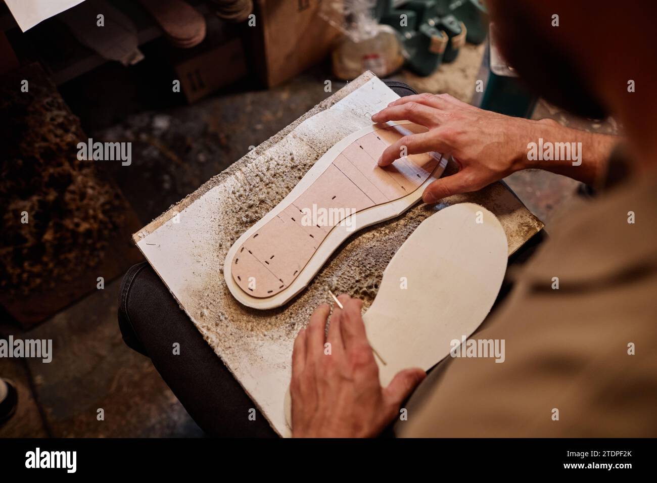 Hand of shoemaking master putting shape sample on boot sole workpiece ...