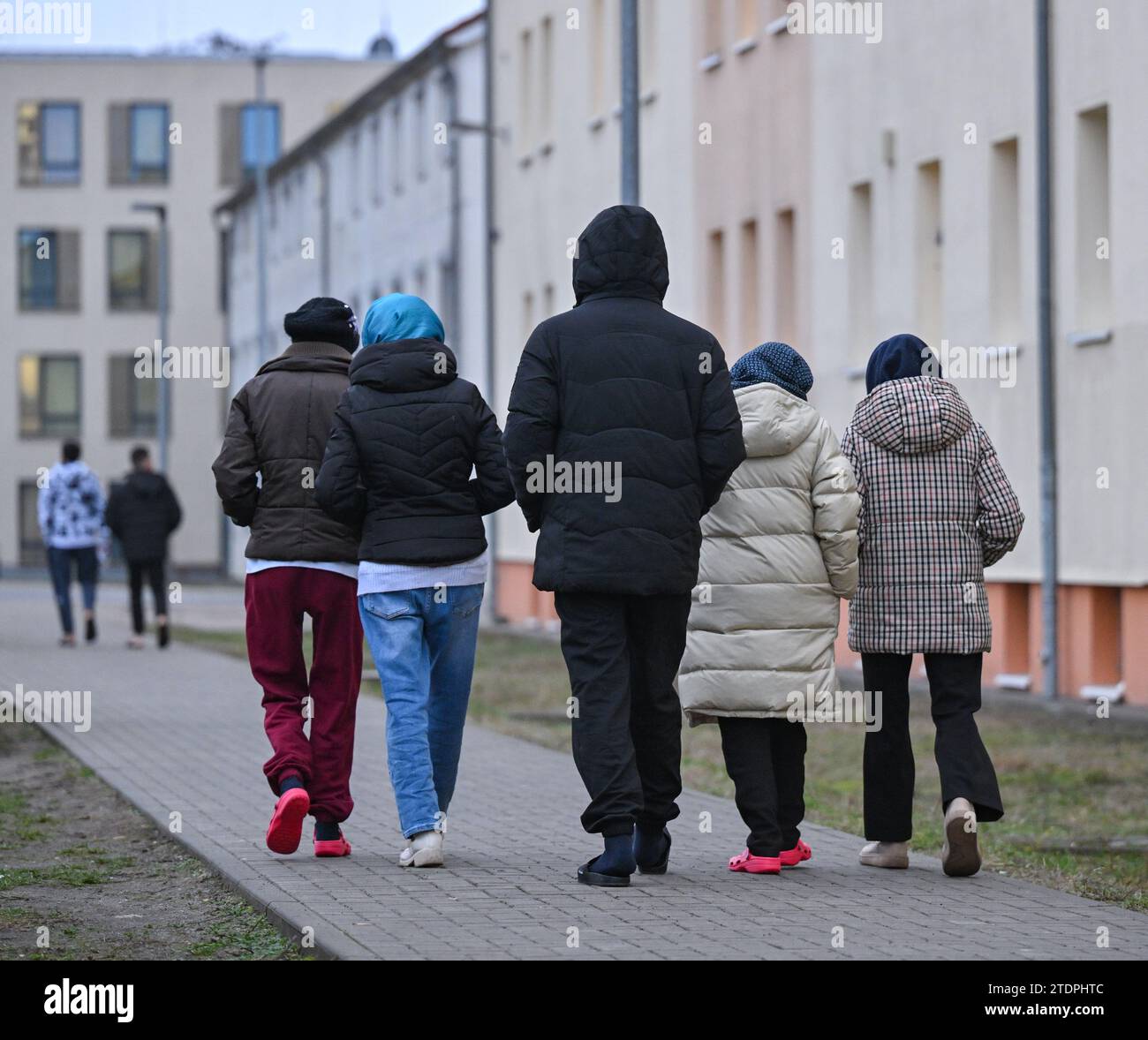 14 December 2023, Brandenburg, Eisenhüttenstadt: Migrants walk across ...