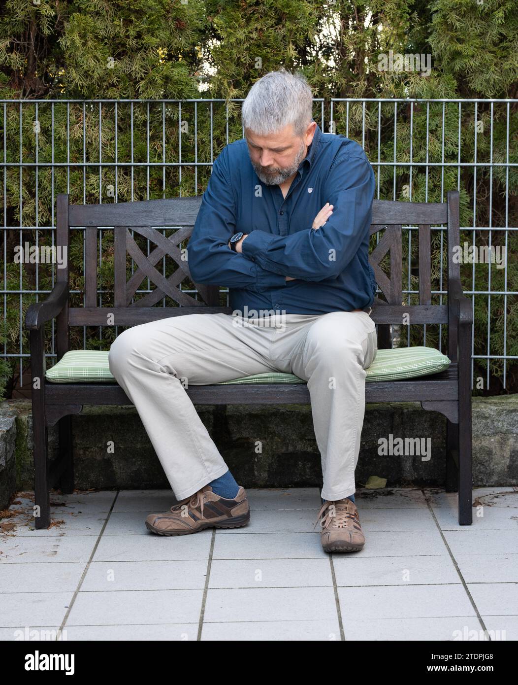 Man with grey hair and full beard, 50-59 years old, sitting on a bench ...