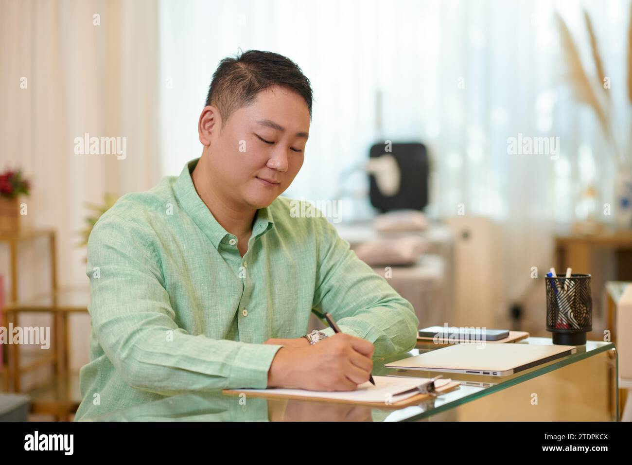 Smiling beauty salon owner planning expenses and writing in document ...