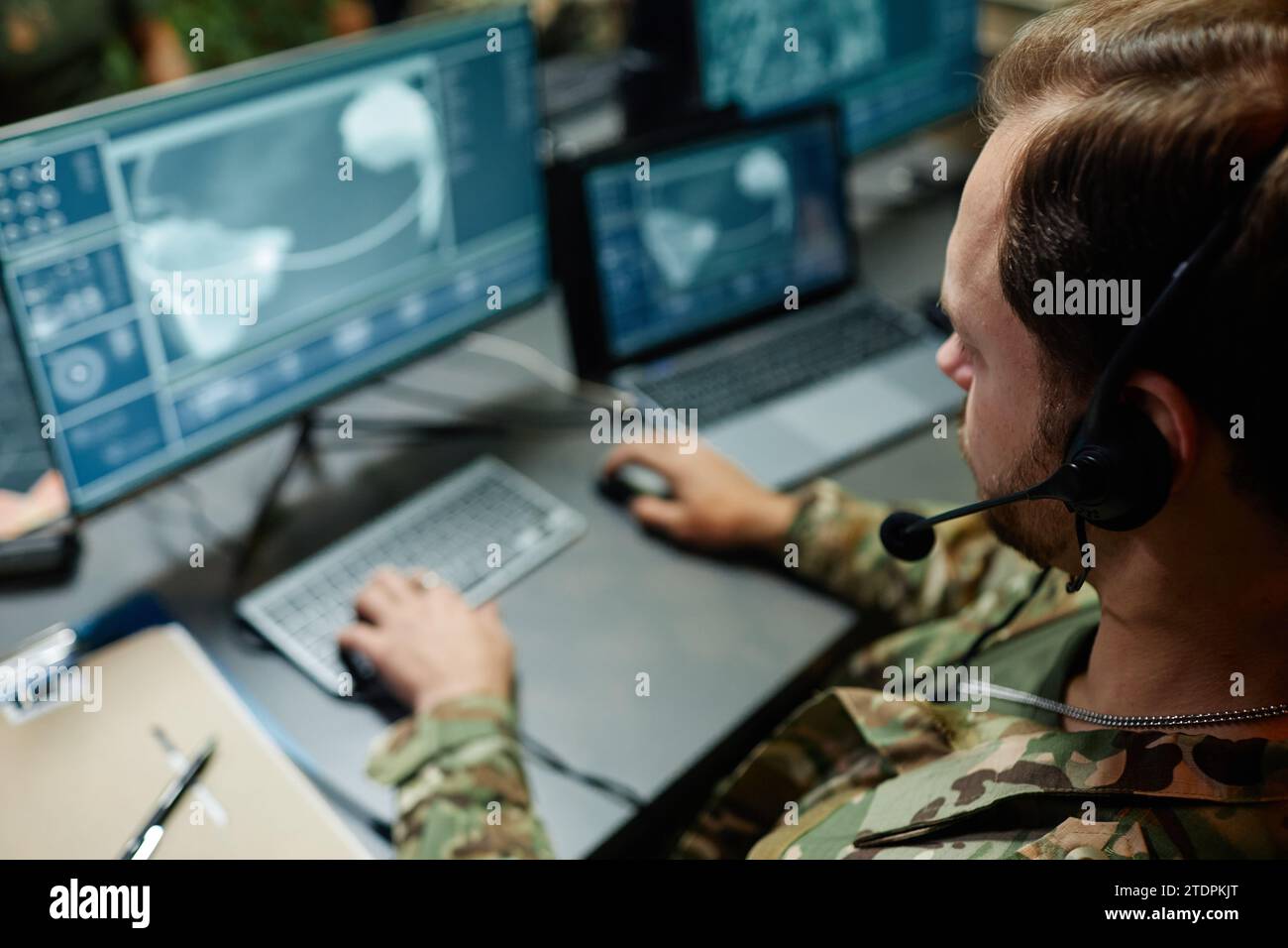 Focus on head of young military officer with headset sitting in front ...