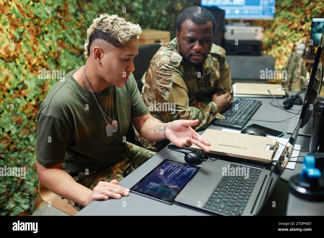 Young multiethnic female military officer pointing at laptop screen and ...