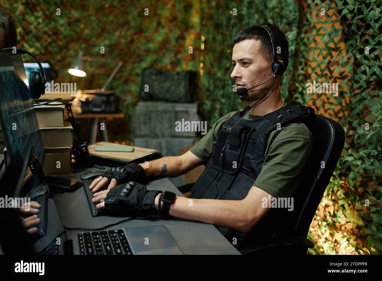 Young serious officer of command and control center in headset looking ...