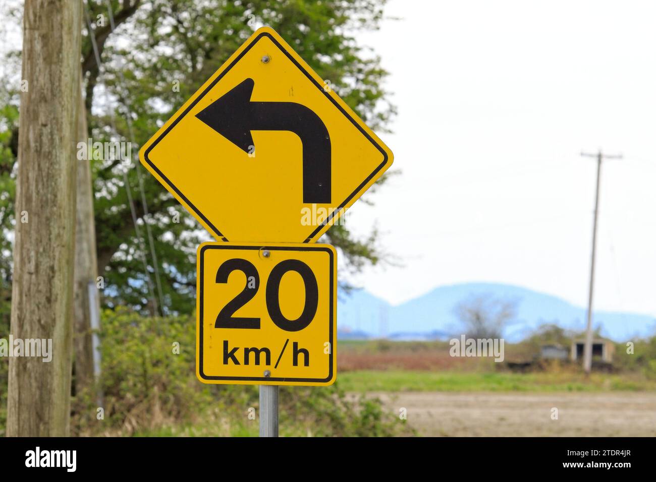 Speed limet and bend in road sign Stock Photo - Alamy