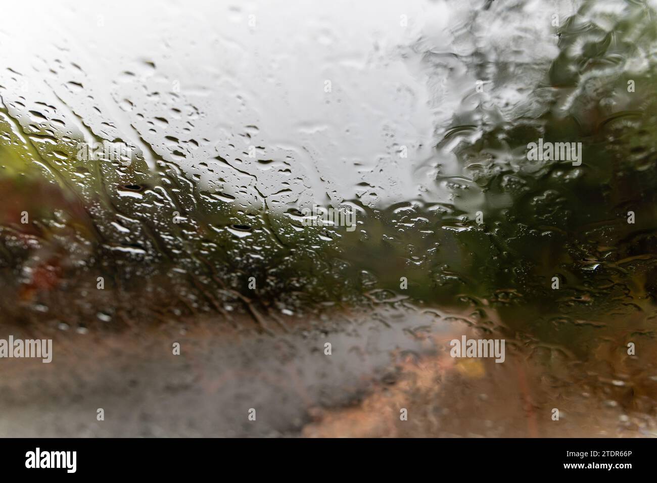 rain drops sliding at car window glass at rainy day from flat angle ...