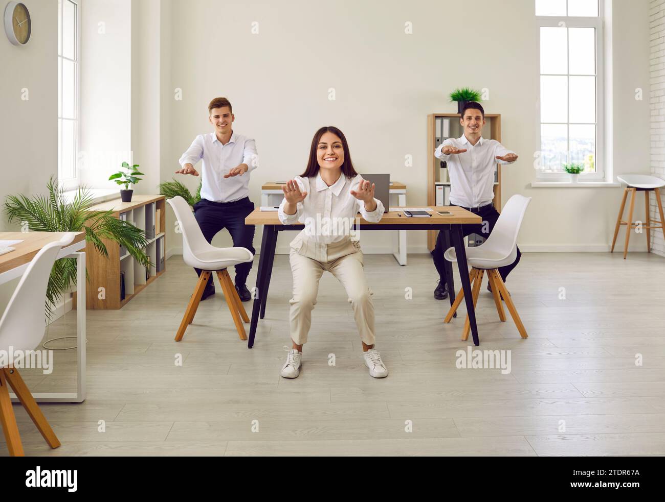 Happy young company employees doing sit-ups exercises in office on ...